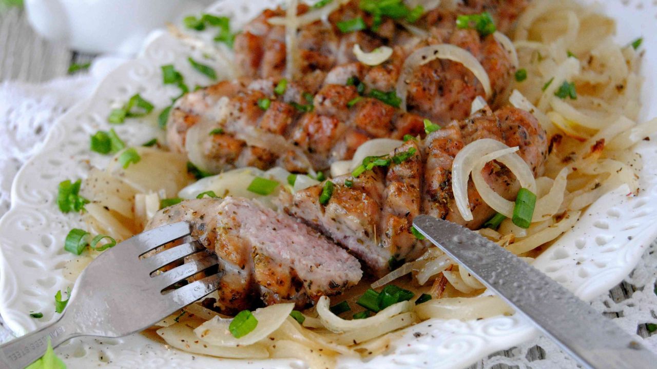 Przepis - Biała kiełbasa pieczona w piwie z cebulą przepis - Gotujmy.pl