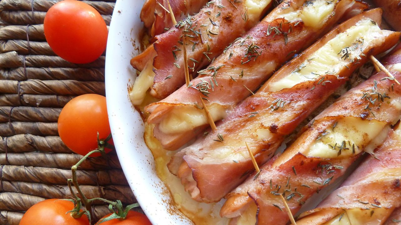 Przepis - Parówki z żółtym serem zapiekane w boczku przepis - Gotujmy.pl